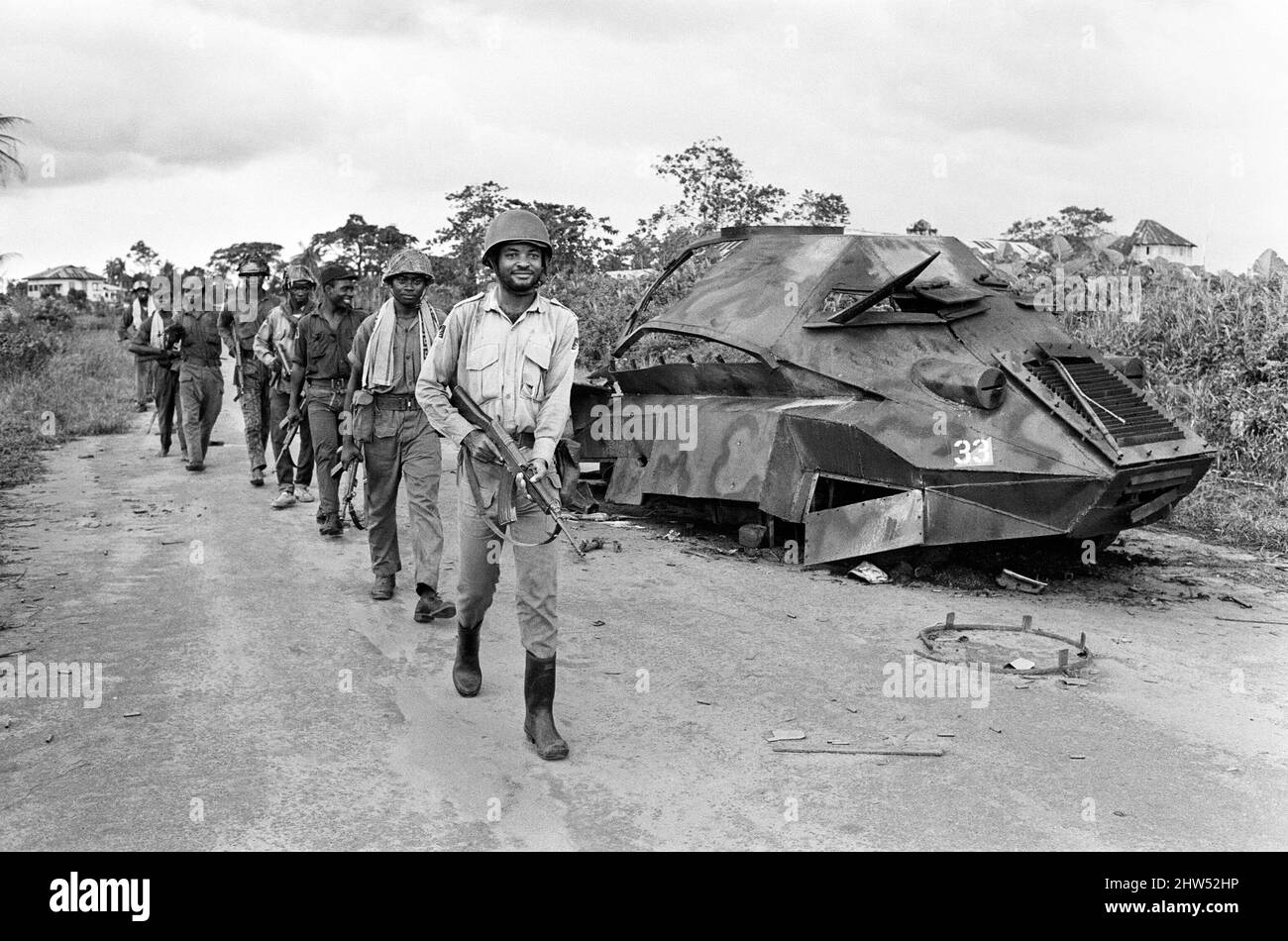 Biafran soldiers seen here marching past a destroyed Nigerian army armoured personnel carrier ...