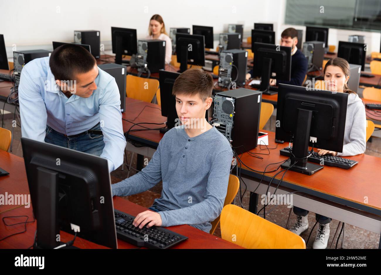 Male trainer helping young male student in computer class Stock Photo ...