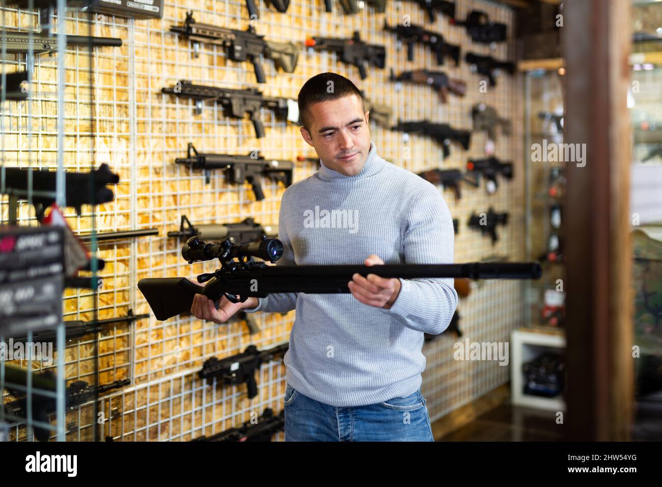 Man choosing sniper rifle in arms shop Stock Photo - Alamy