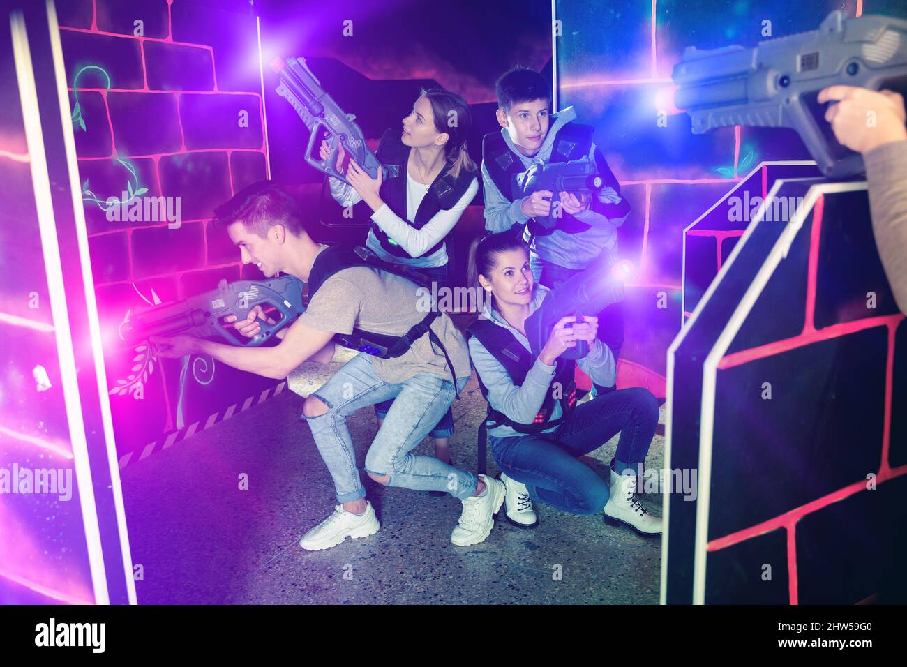 Modern young people with laser pistols playing laser tag on dark Stock ...