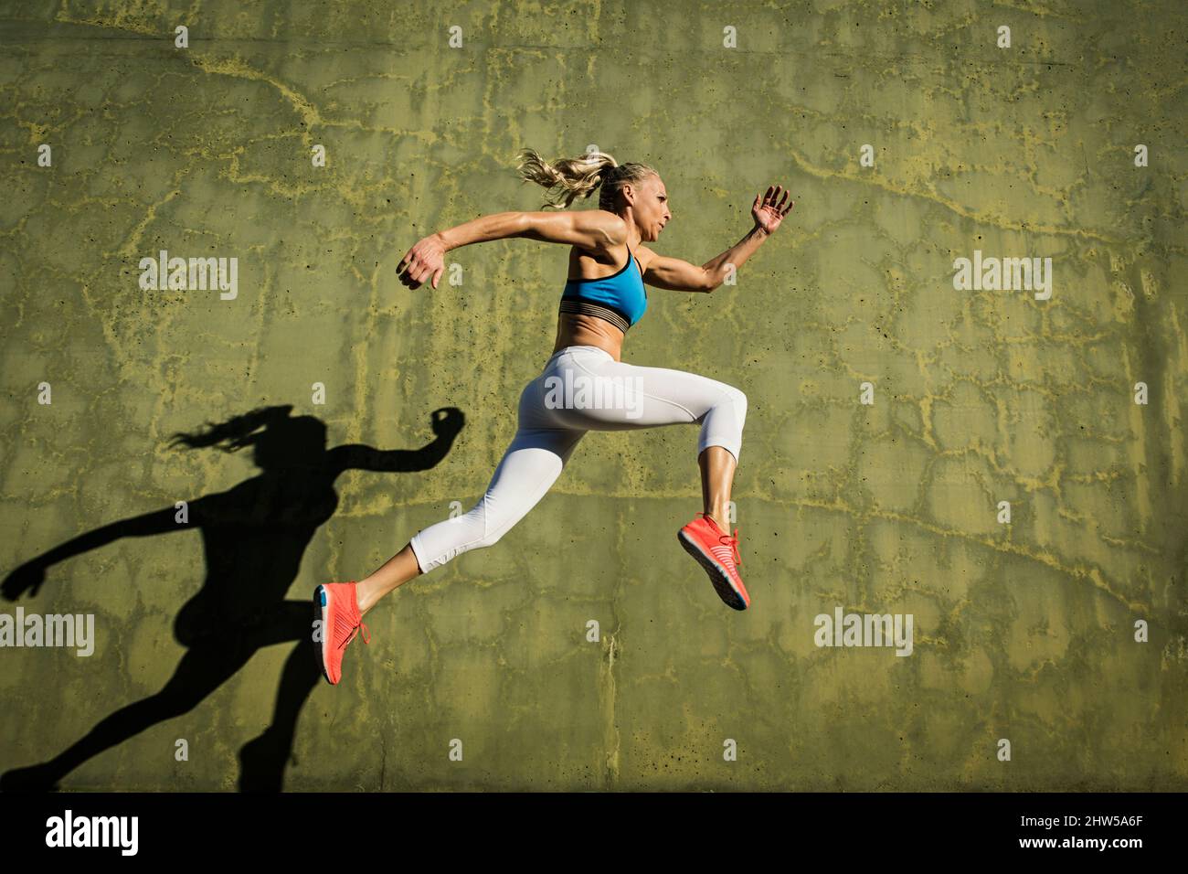 Athlete woman jumping against wall Stock Photo - Alamy