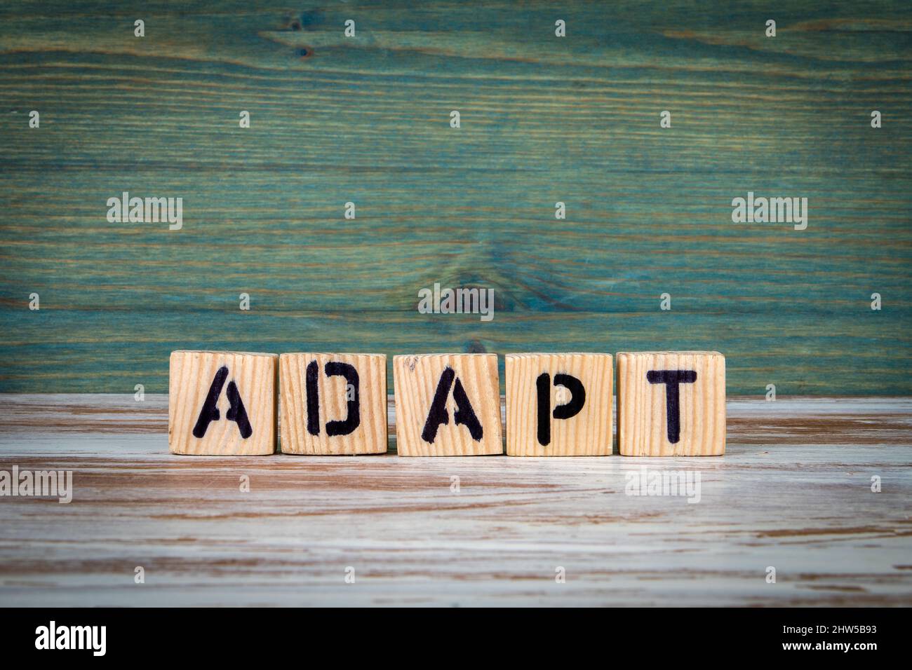 ADAPT. Text from wooden letters on a green background Stock Photo - Alamy