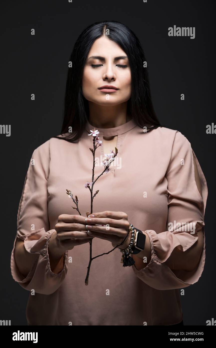 Studio portrait of woman holding blooming twig with eyes closed Stock ...