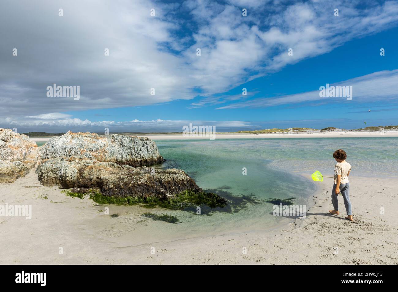 South Africa, Hermanus, Boy (8-9) with fishing net on Grotto Beach ...