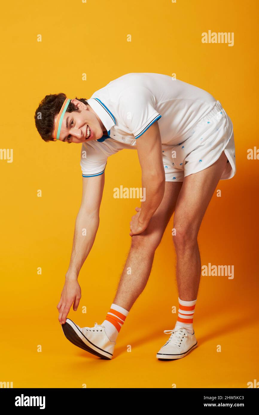 Stretch it out. A male stretching out his calf muscle in retro sports ...