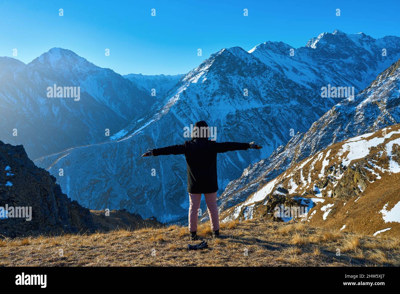 girl with long brown hair in a mint jacket and a purple scarf stands on ...