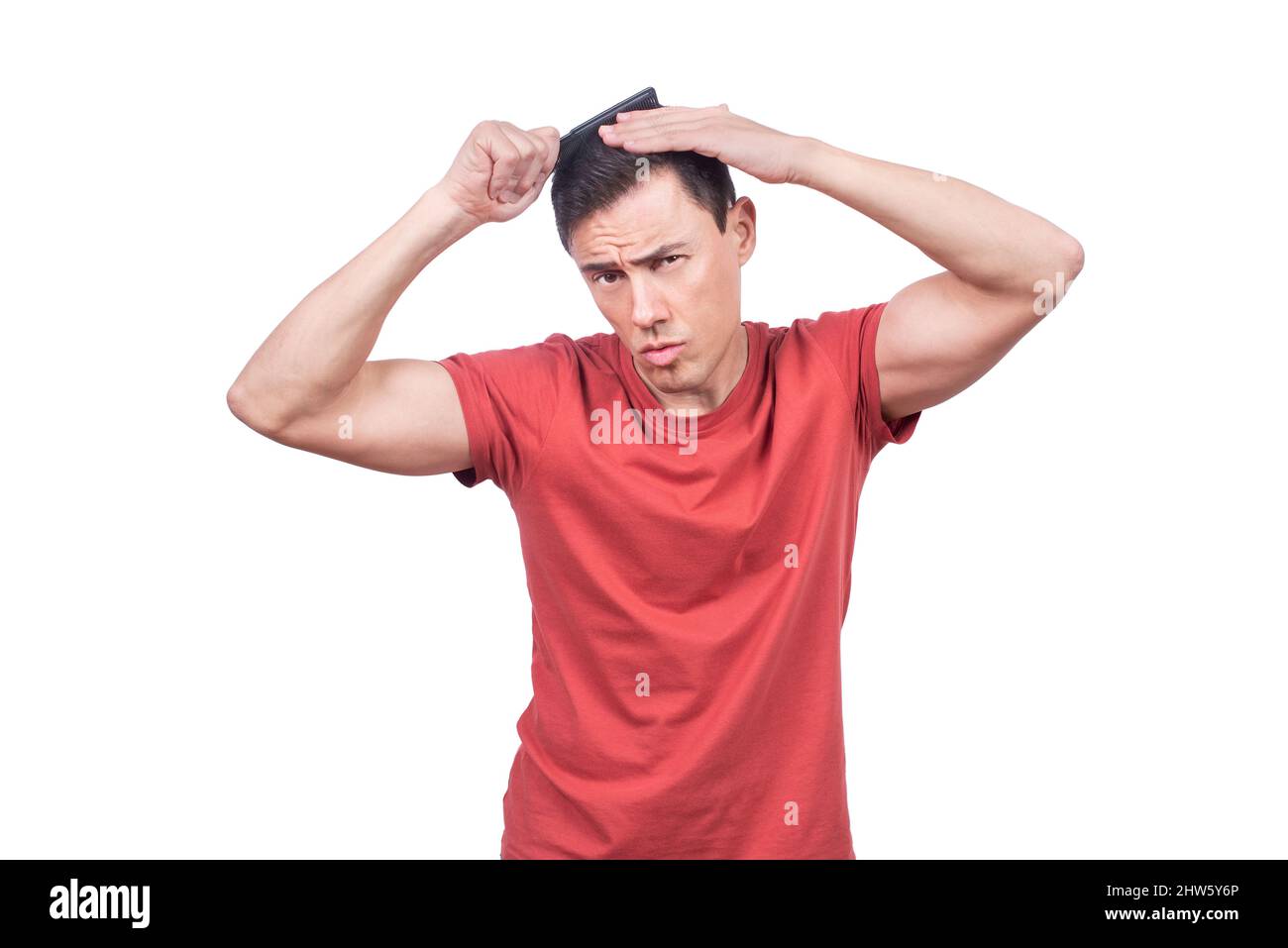 Diligent man combing hair against blank background Stock Photo - Alamy