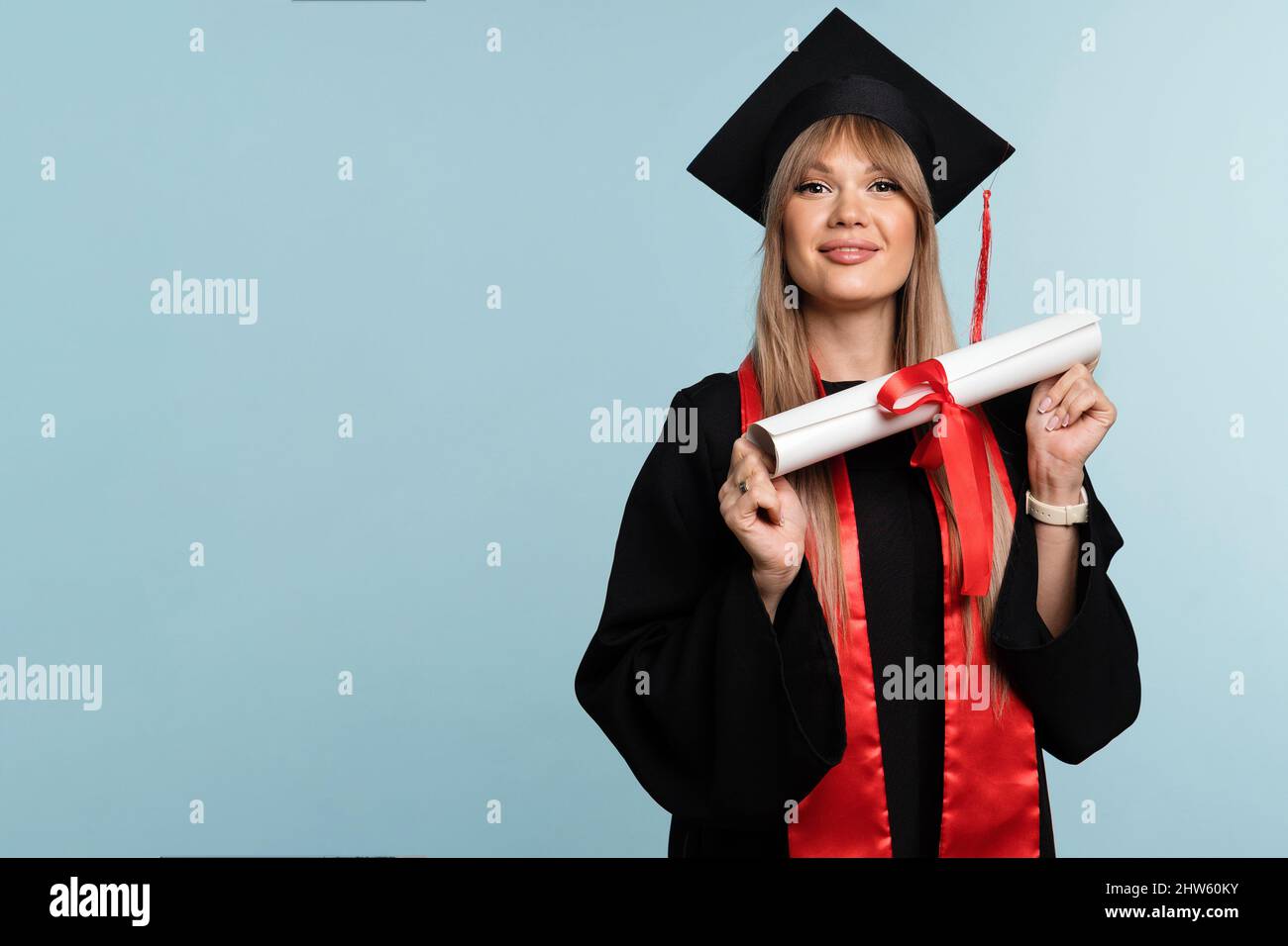 Girl graduate in graduation hat with diploma on light blue background ...