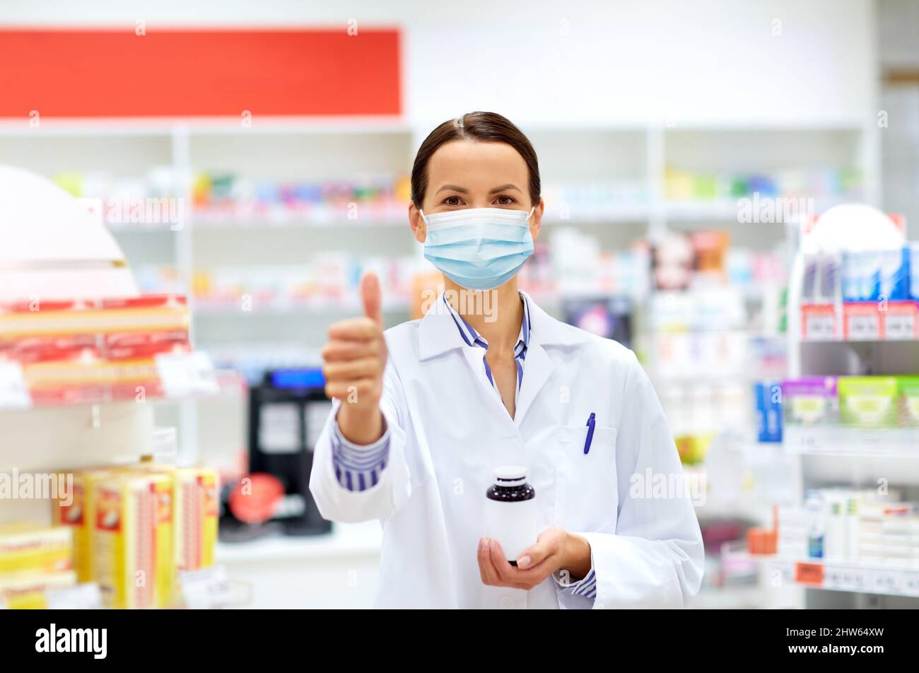 apothecary in mask showing thumbs up at pharmacy Stock Photo - Alamy