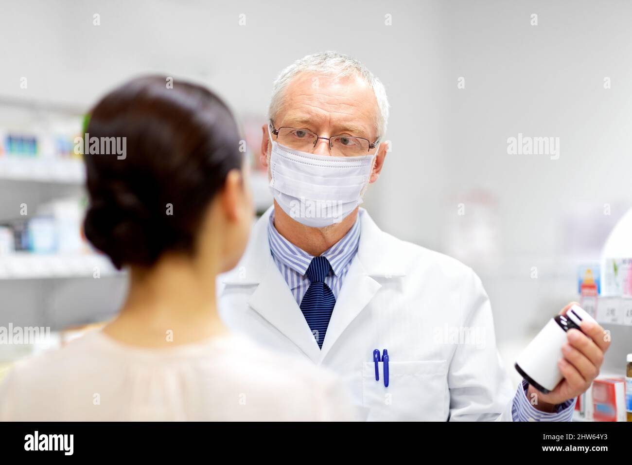 apothecary in mask showing drug to customer Stock Photo - Alamy