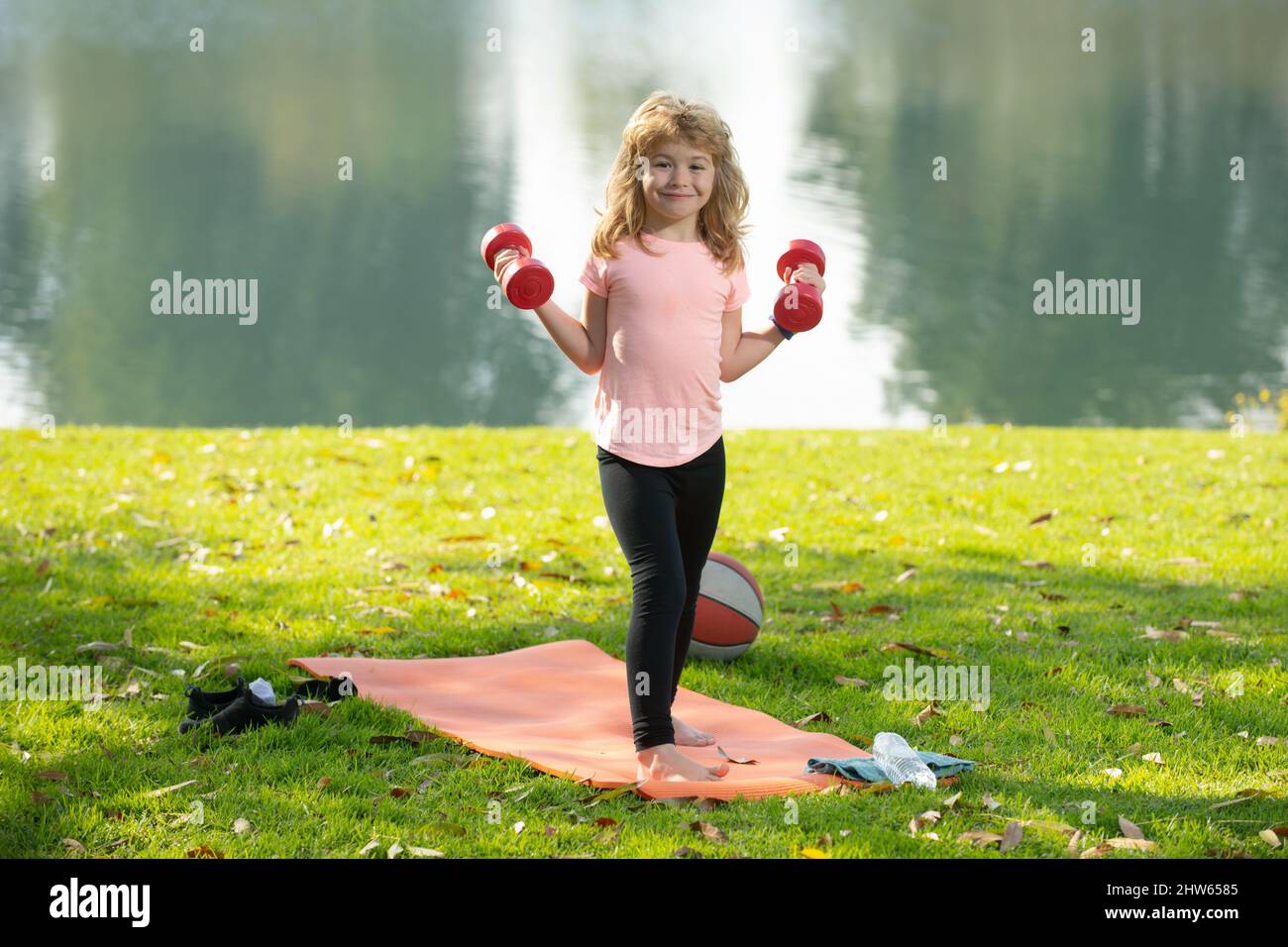 Child boy working out with dumbbells on park background. Kids sport ...