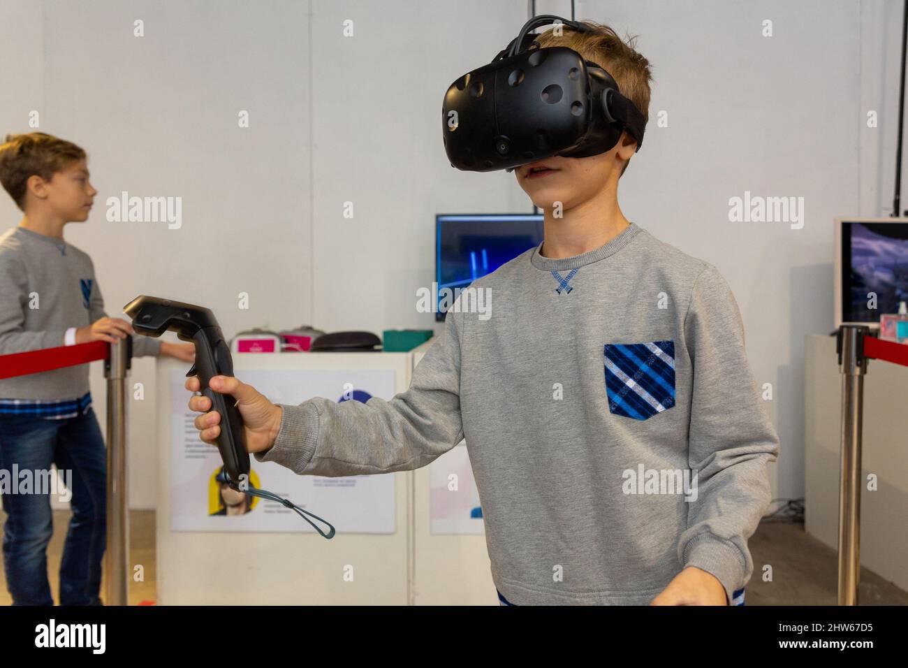 Eight years boy wearing VR headset, holding controllers in hands and ...
