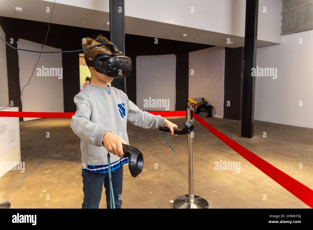 Eight years boy wearing VR headset, holding controllers in hands and ...
