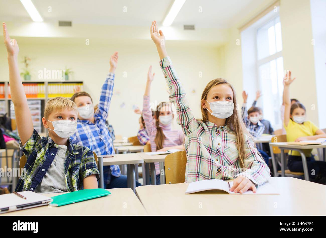 group of students in masks raising hands at school Stock Photo - Alamy