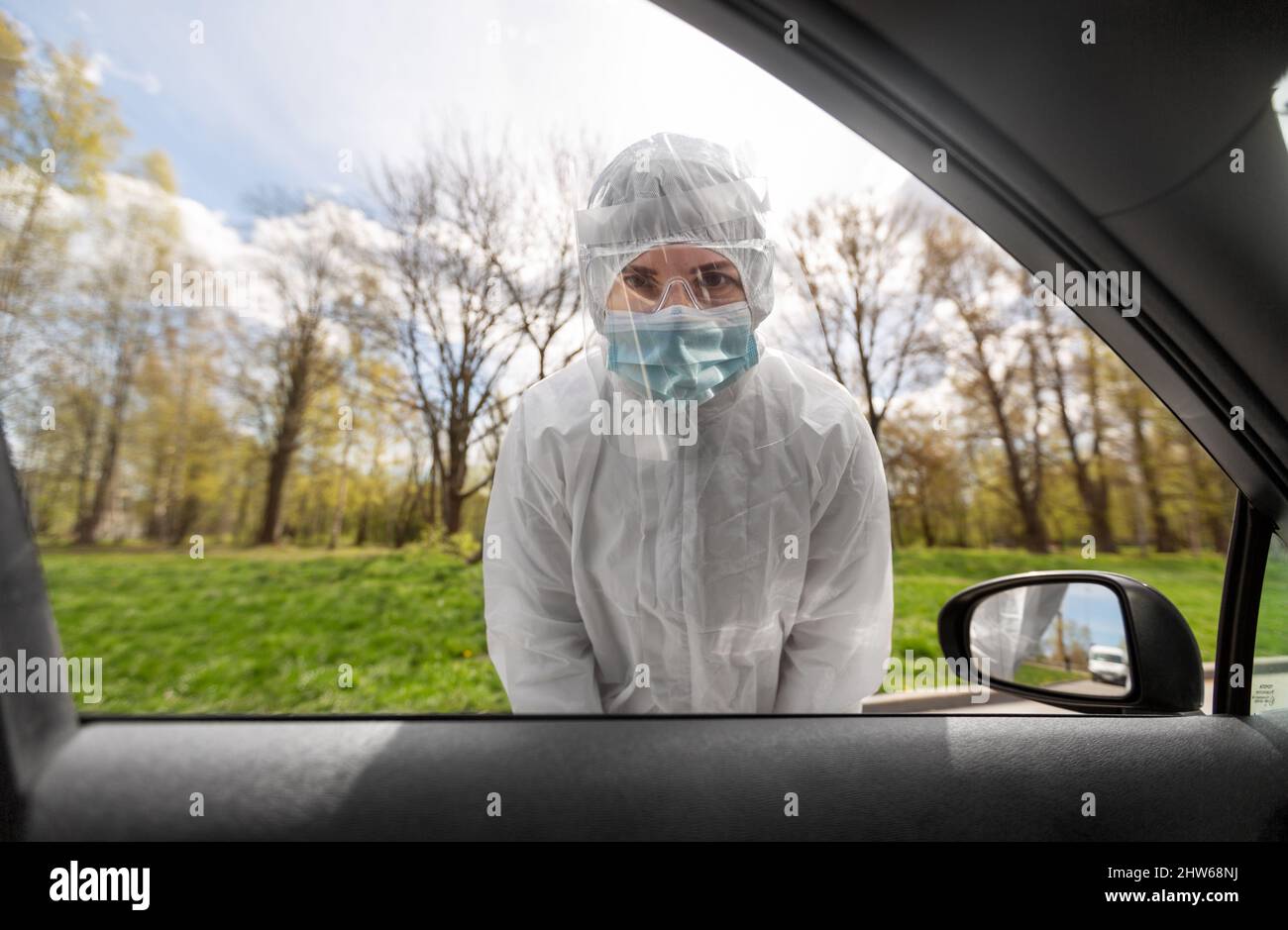 healthcare worker in hazmat suit looking into car Stock Photo - Alamy