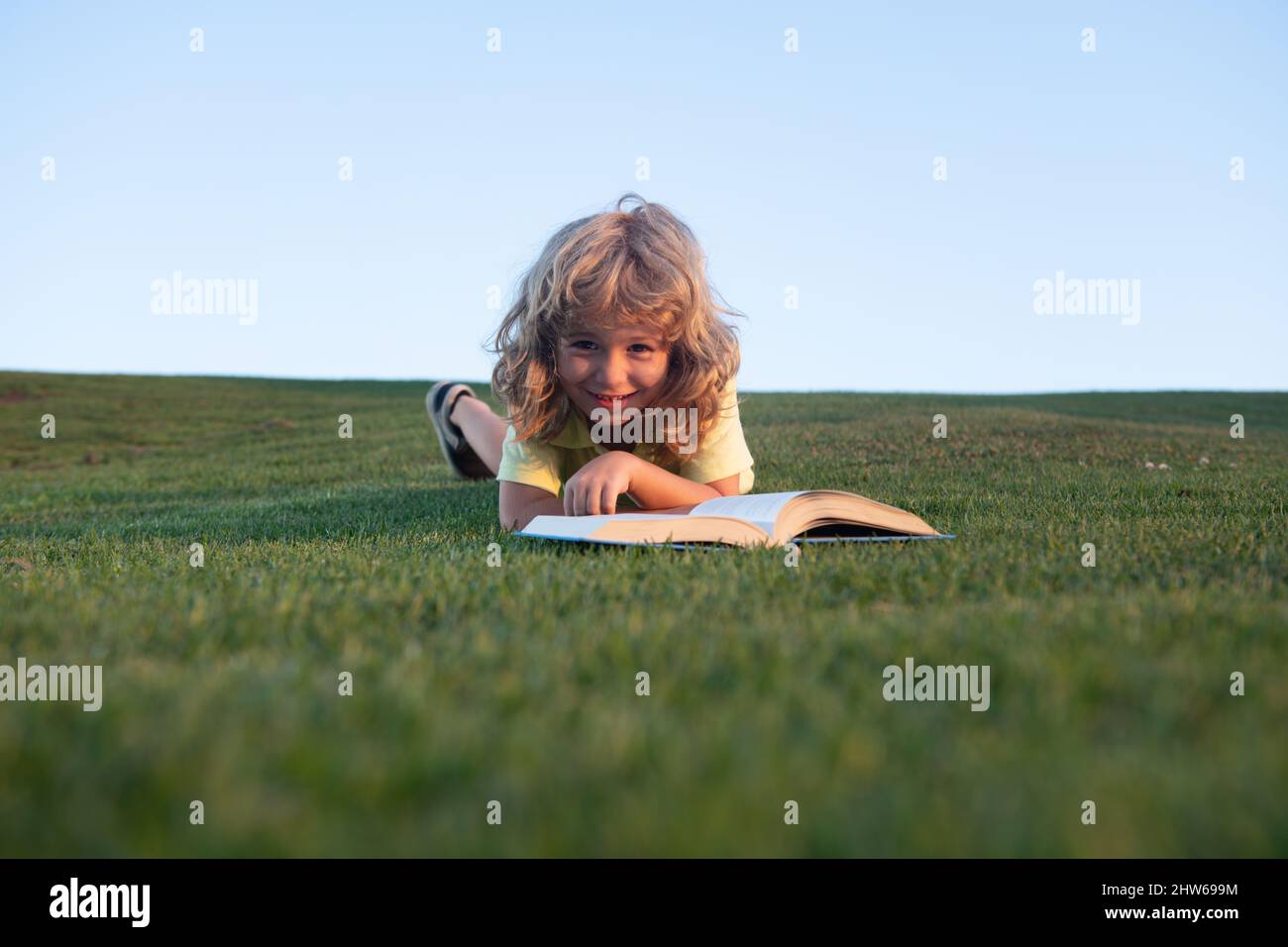 Smart kid boy reading book in park on green grass lawn outdoor Stock ...