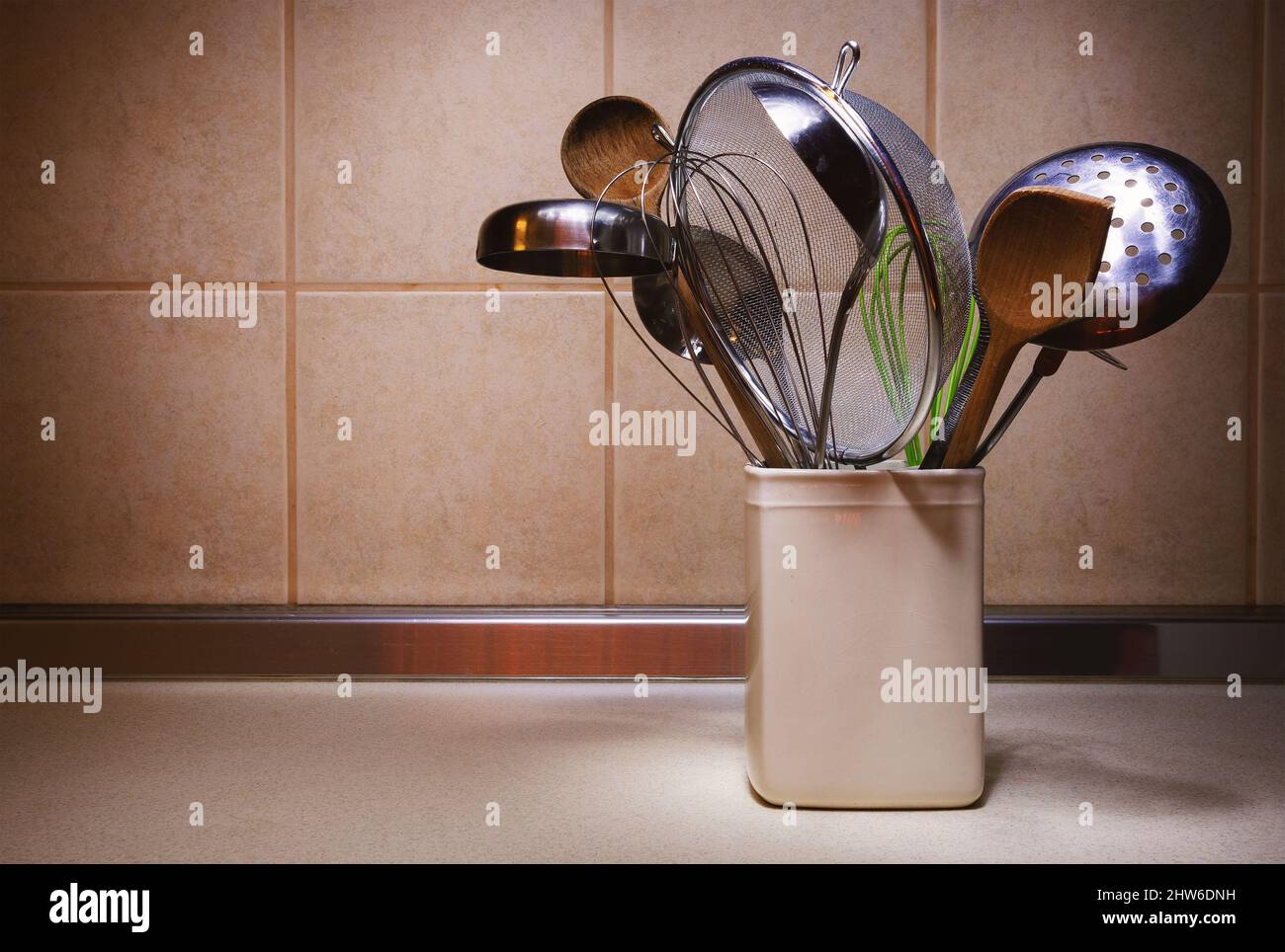 Various kitchen utensils in ceramic container on kitchen desk Stock ...