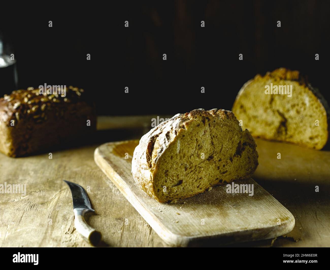 Cut rye bread on a wooden table with a knife isolated on the black ...