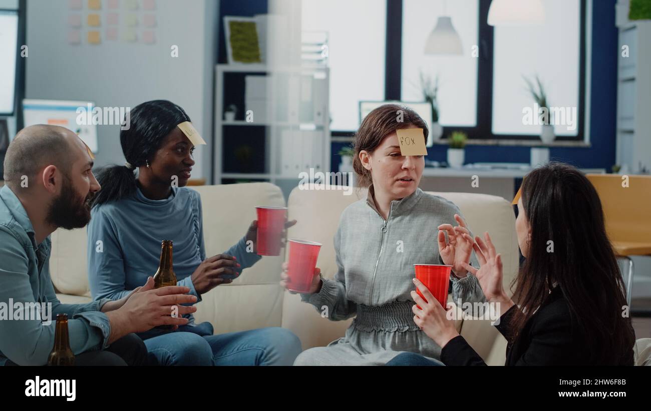 Cheerful coworkers play guessing game with drinks and snacks on free ...