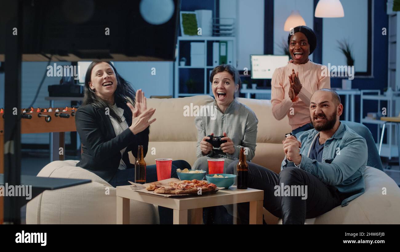 Happy coworkers playing video games after work at office. Colleagues ...