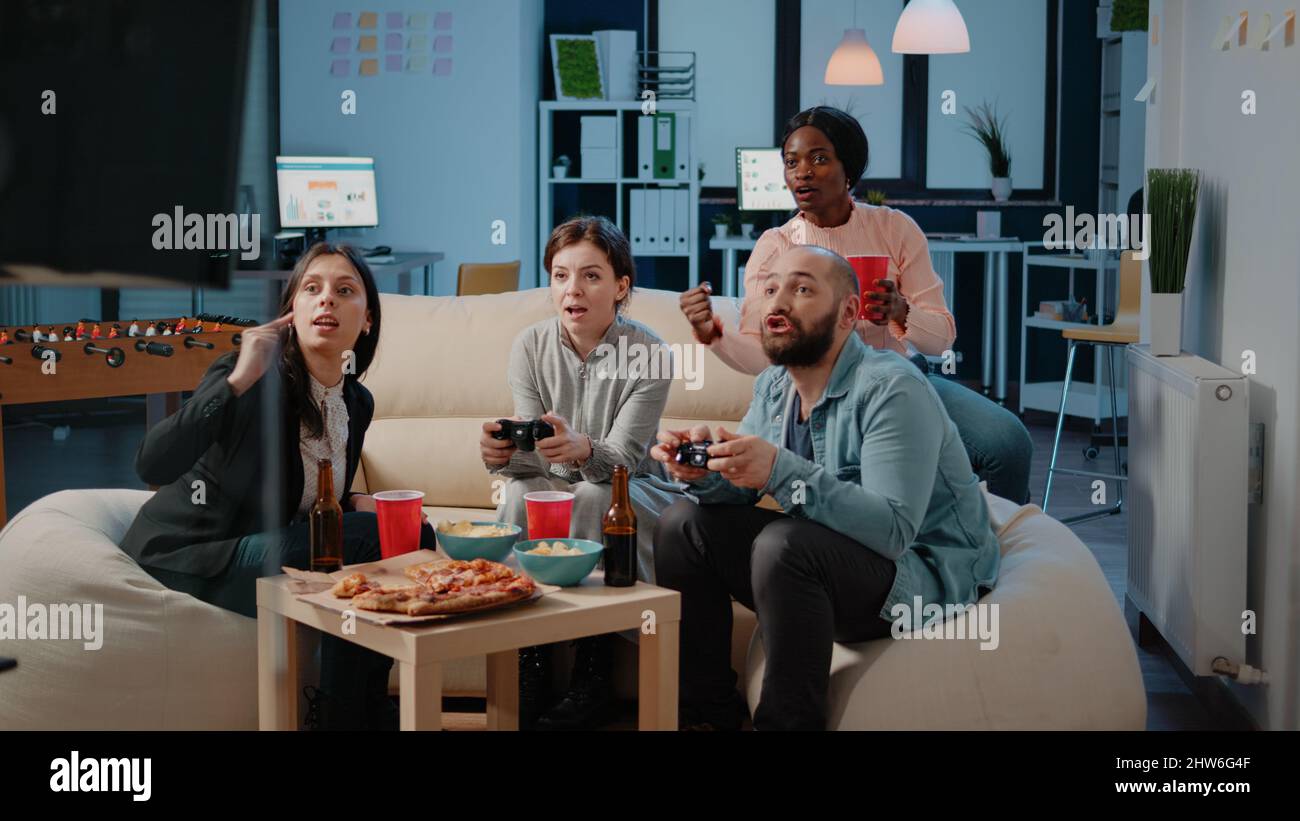 Diverse group of workmates using joysticks to play video games on ...