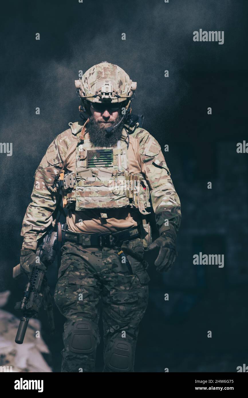 A bearded soldier in a special forces uniform walks through an ...