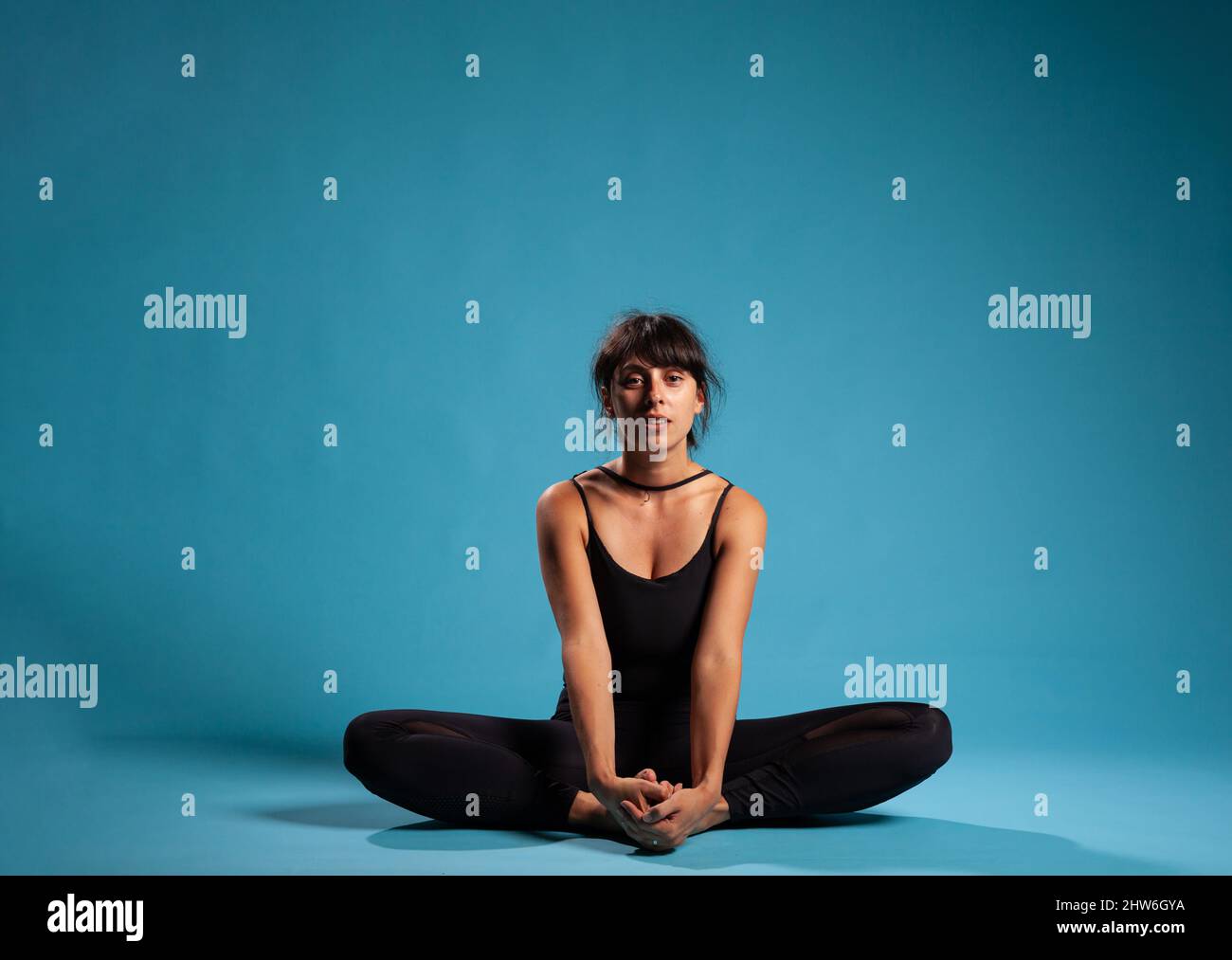 Athletic trainer sitting in padmasana position on yoga mat stretching ...