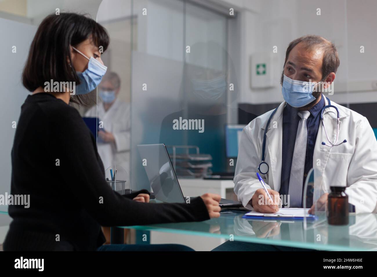 Medic at consultation with woman taking notes on clipboard paper ...