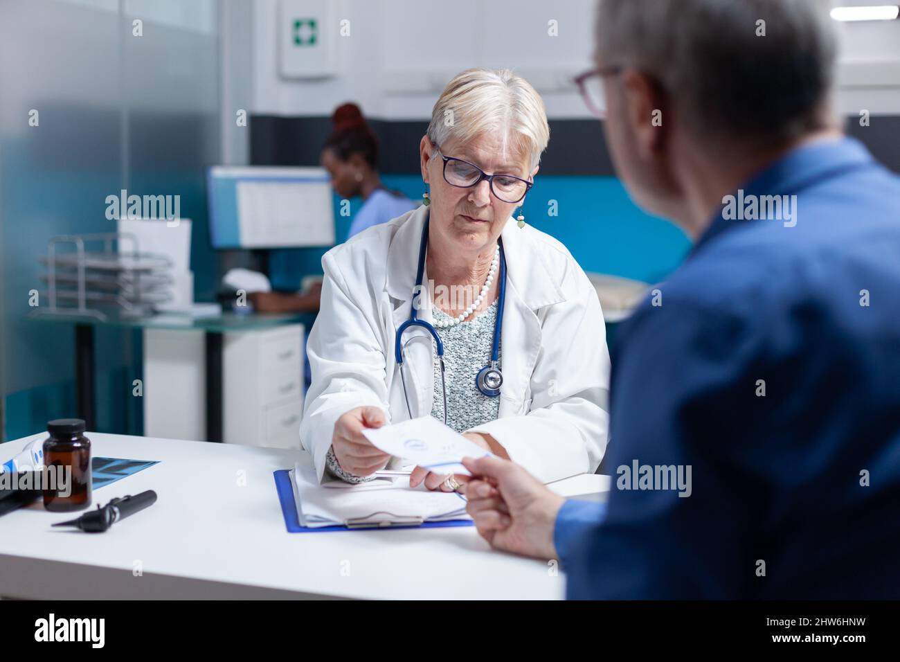 Woman doctor giving prescription paper with treatment to ill man in ...