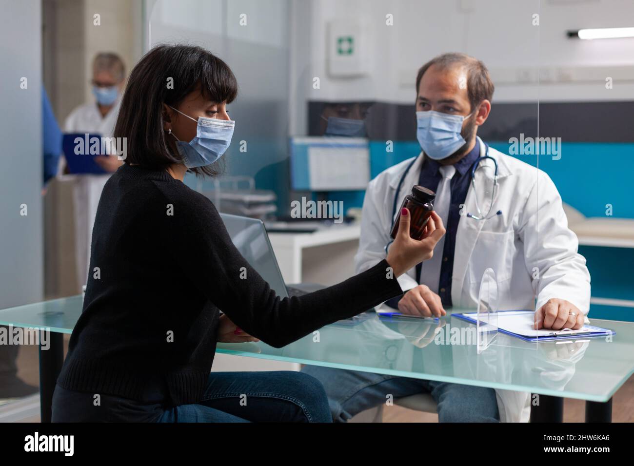 Adult and physician with face mask discussing about bottle of pills and ...