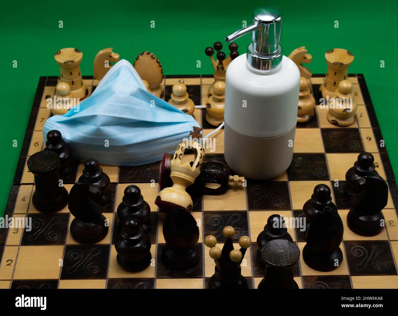 Medical mask and an antiseptic bottle on a chess board isolated on a ...