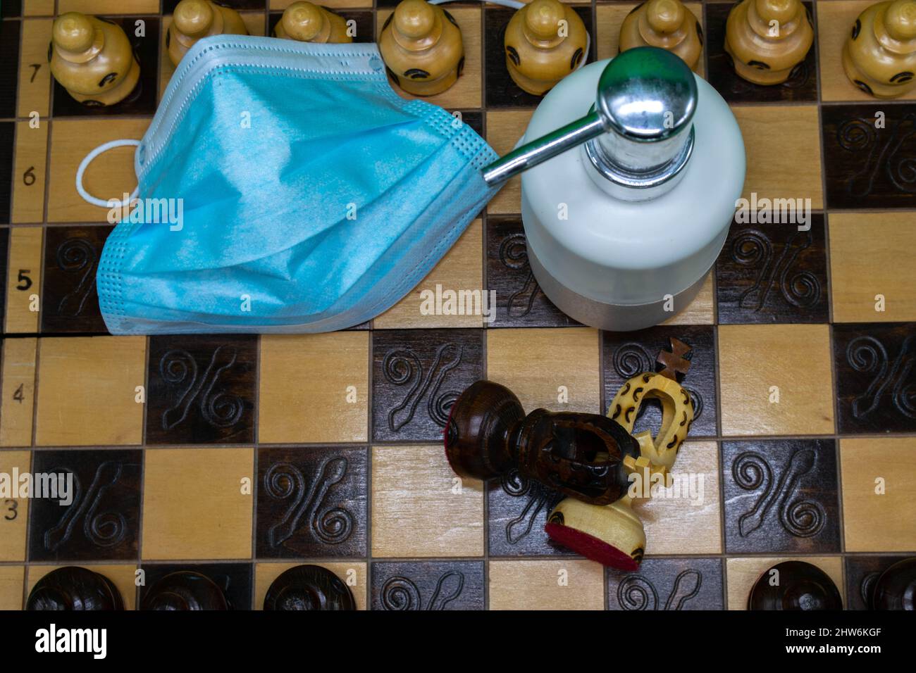 Medical mask and an antiseptic bottle on a chess board isolated on a ...