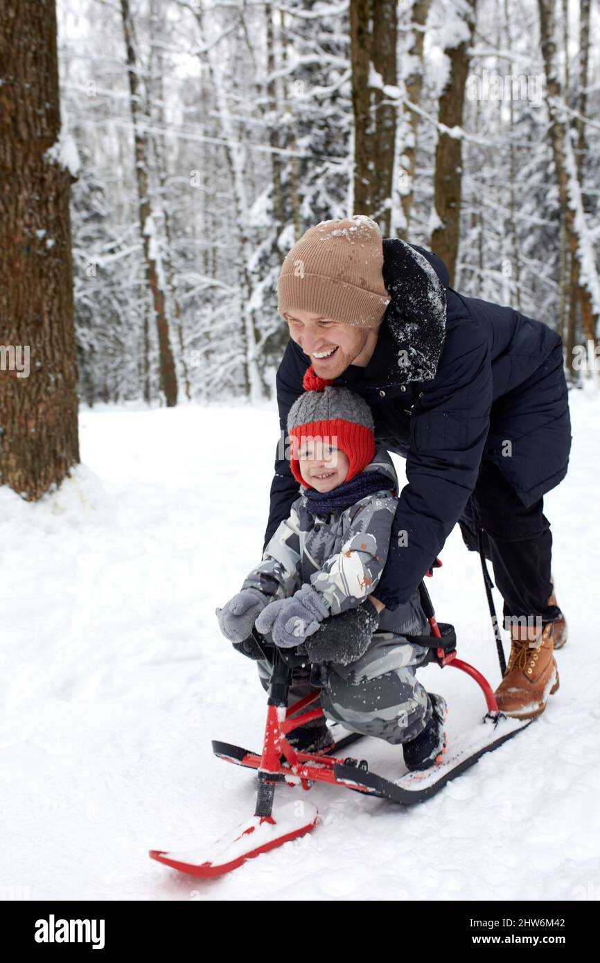 Father and his son in funny hat having fun and laughing in snowy winter ...