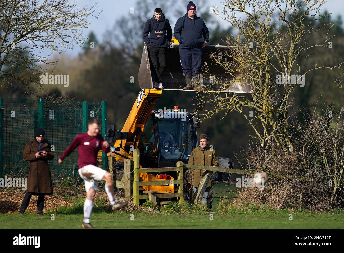 Spectators watch the action on top of a JCB digger during the match at ...