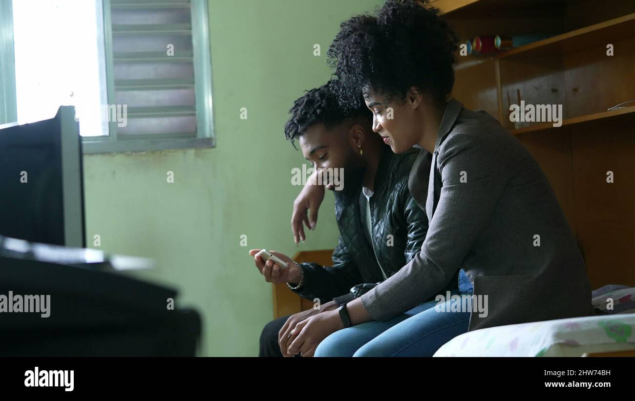 An African couple sitting together staring at cellphone device Stock ...