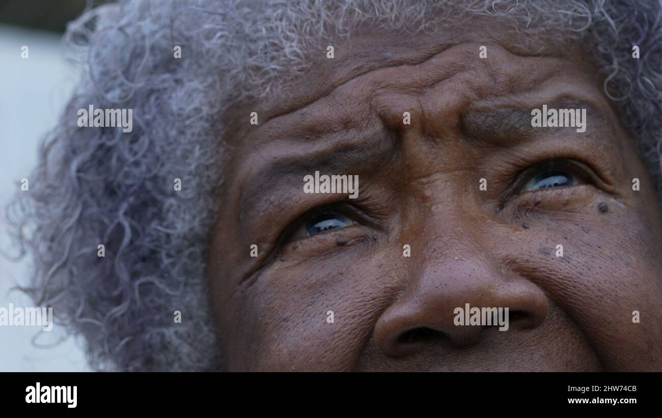 An African older woman looking up at sky with HOPE and FAITH macro eyes ...