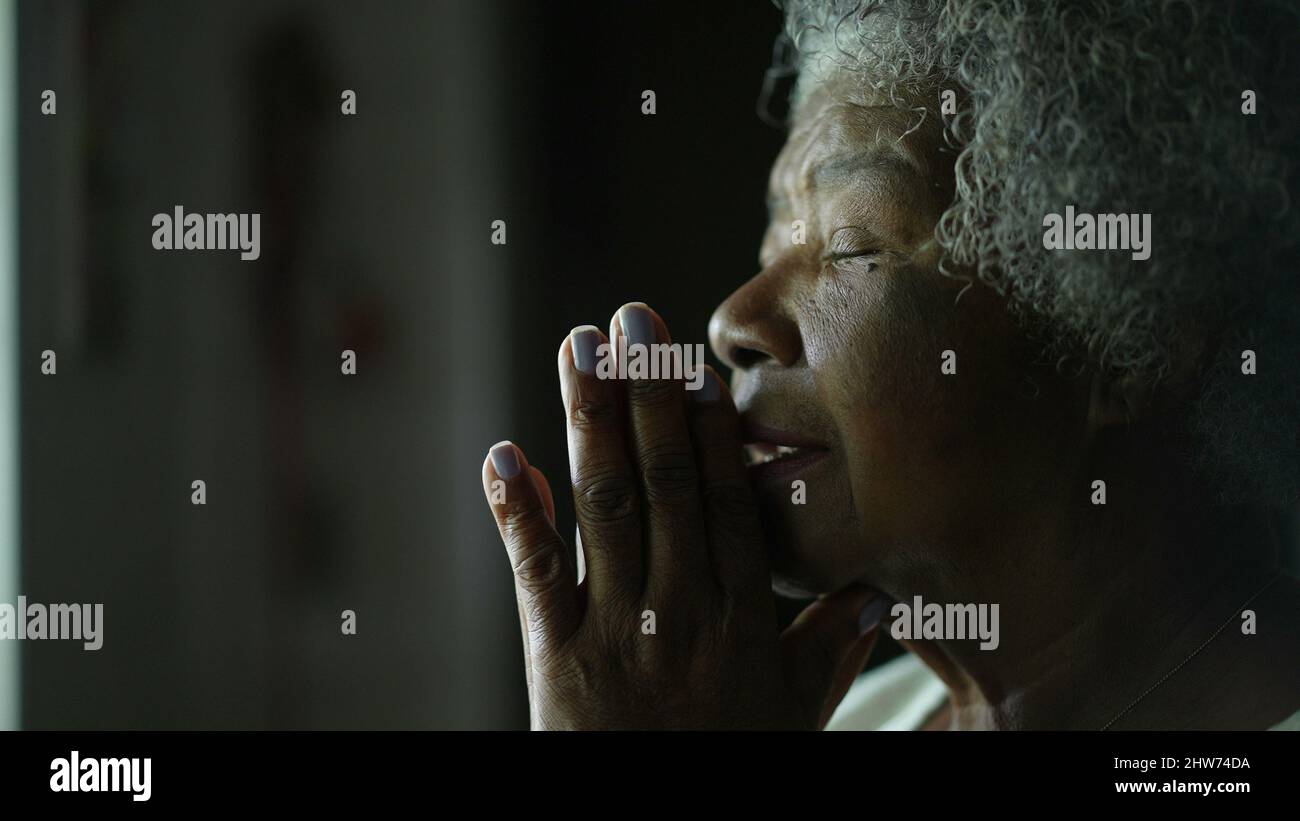 An older African woman praying to God closing eyes with HOPE and FAITH ...