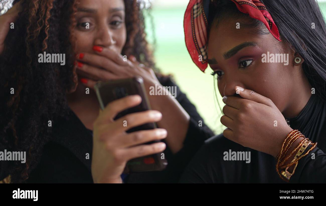 Mother and daughter reacting with shock to content online holding ...