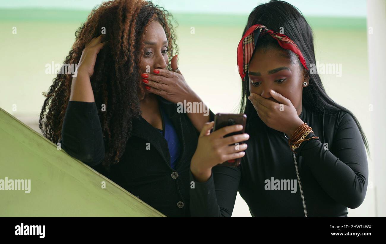 Mother and daughter reacting with shock to content online holding ...