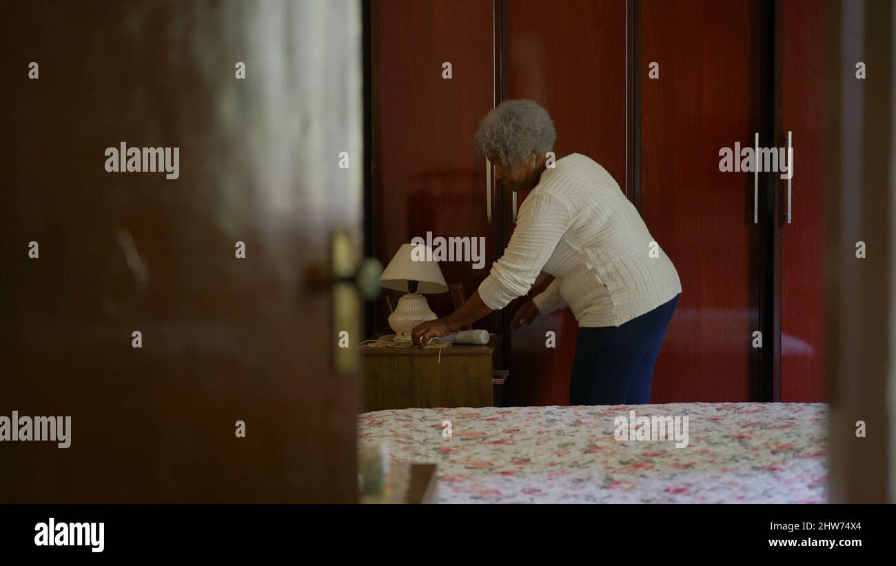 One senior black woman organizing home in bedroom Stock Photo - Alamy