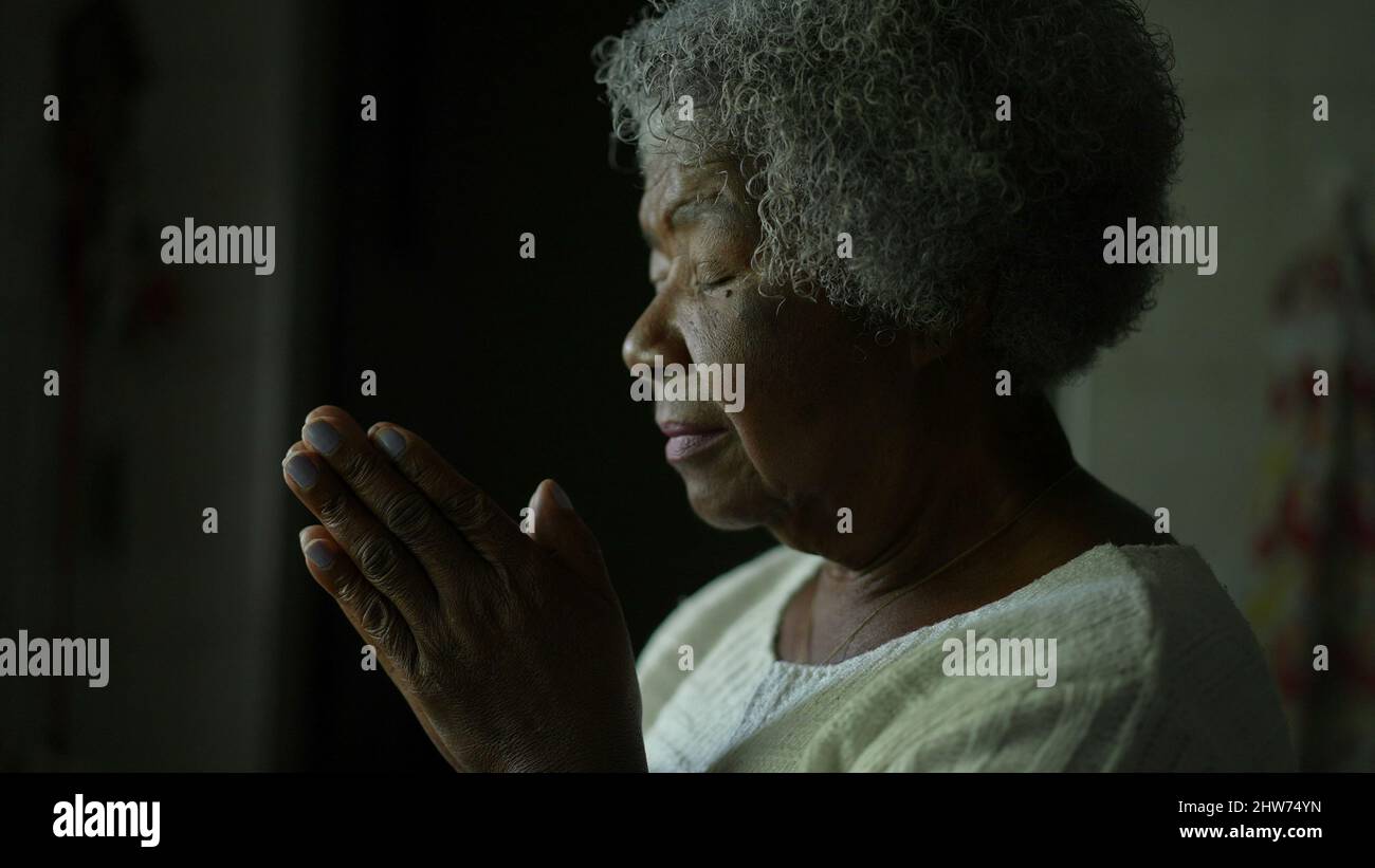 Pensive senior woman praying with eyes closed at home Stock Photo - Alamy