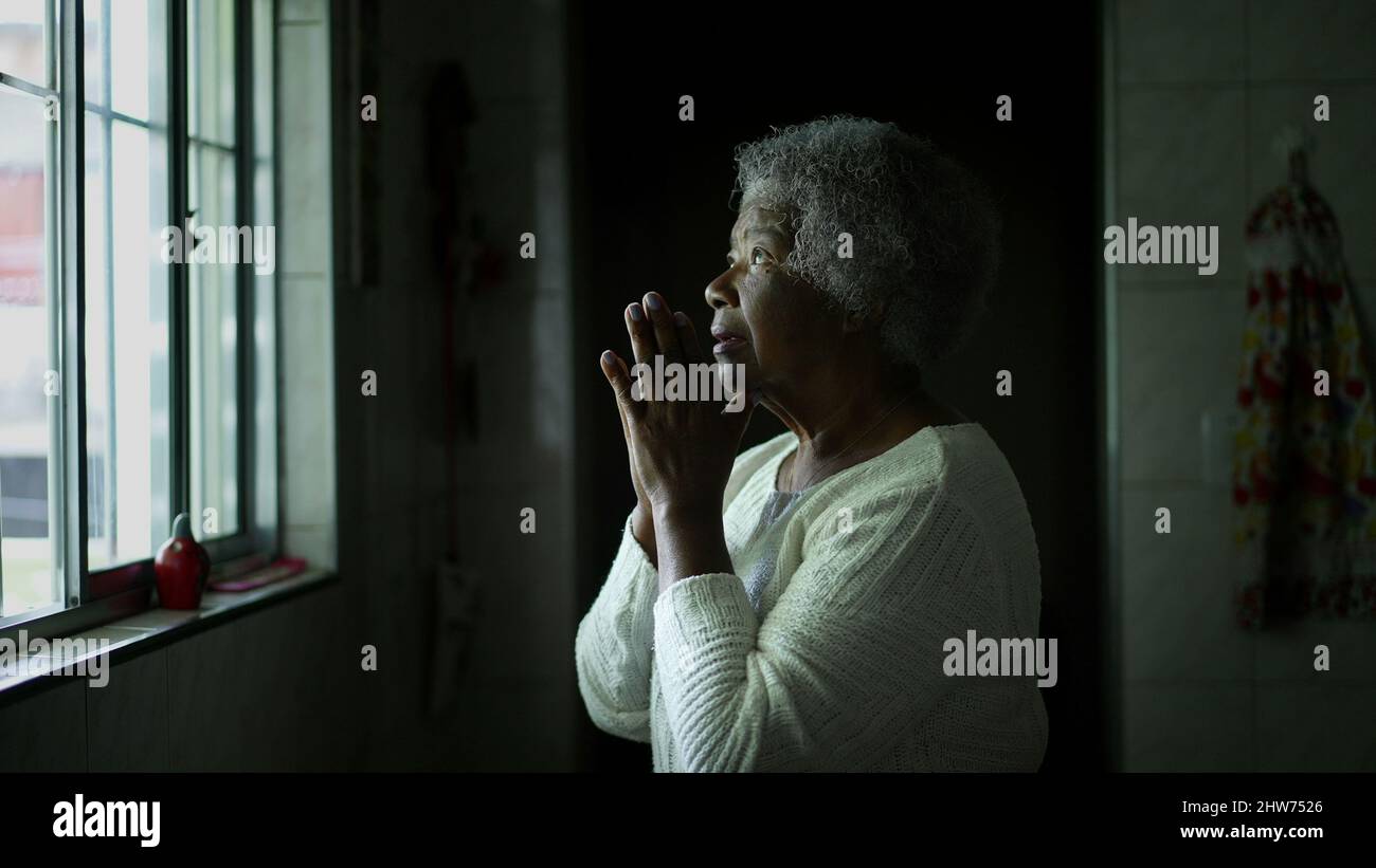 Spiritual older woman in 80s praying at home by window Stock Photo - Alamy
