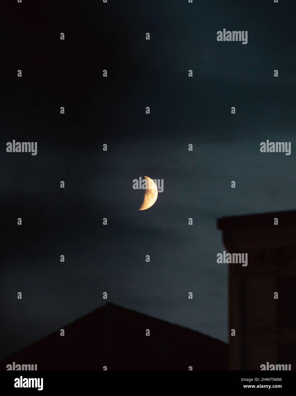 Vertical shot of the half moon in the cloudy skies Stock Photo - Alamy