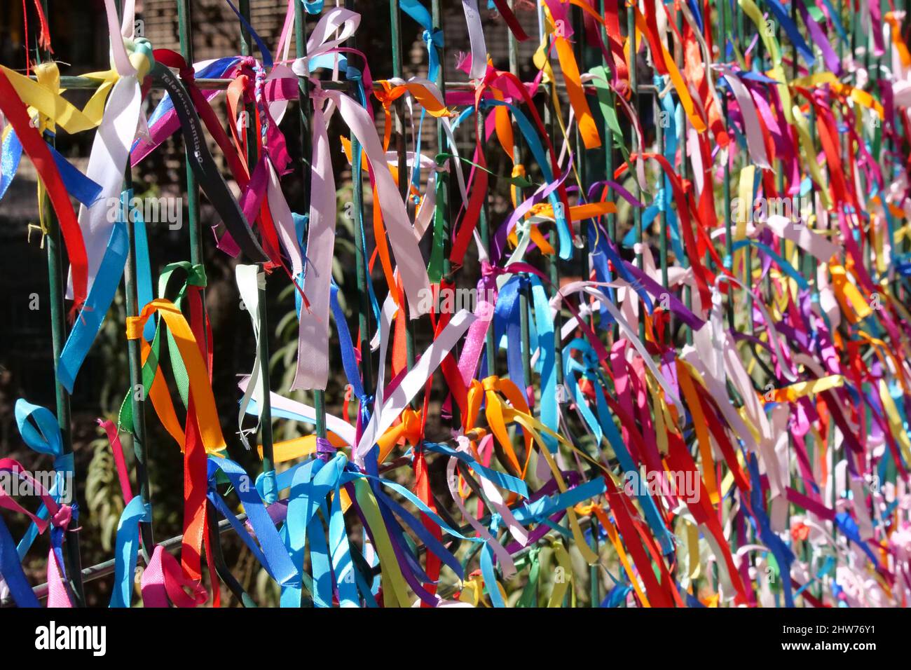 Close up of colourful strings tied to a fence. The background is ...
