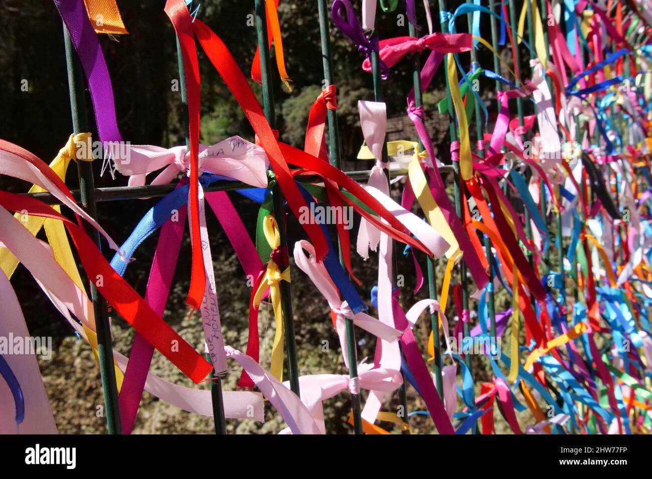 Close up of colourful strings tied to a fence. The background is ...