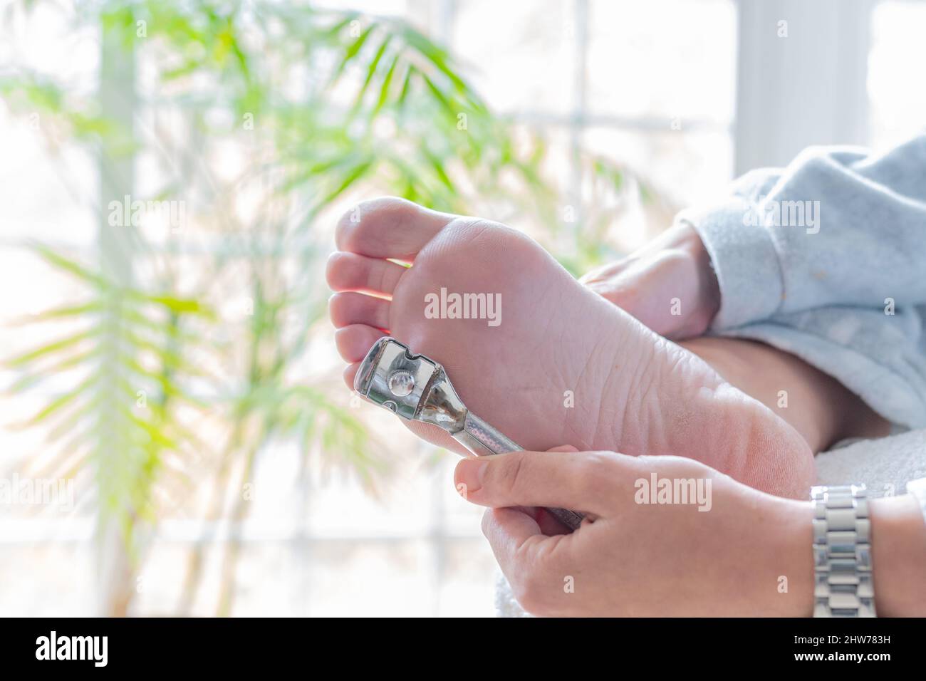 hands of a woman using a cleaver on her feet to remove calluses. body ...