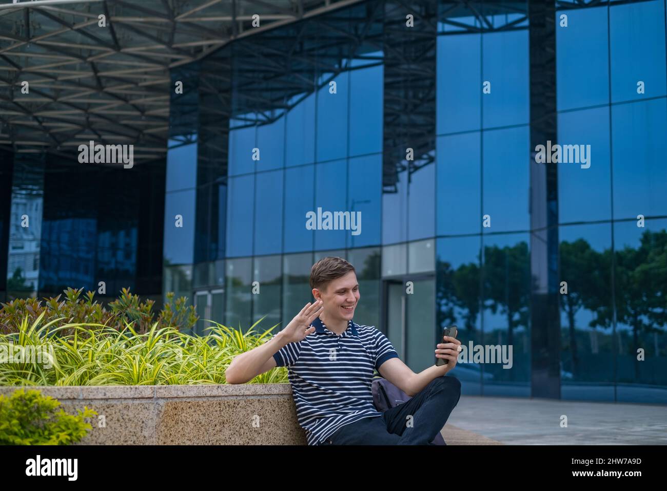 Young caucasian man in casual clothing sitting near modern office ...