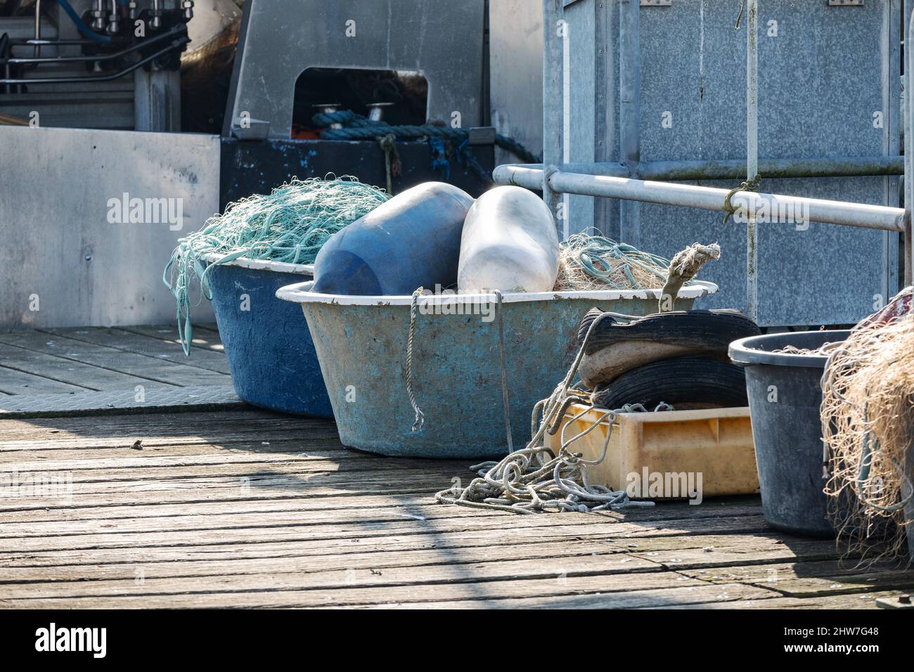 Fishing nets and fenders in old vats on the jetty in the port of ...