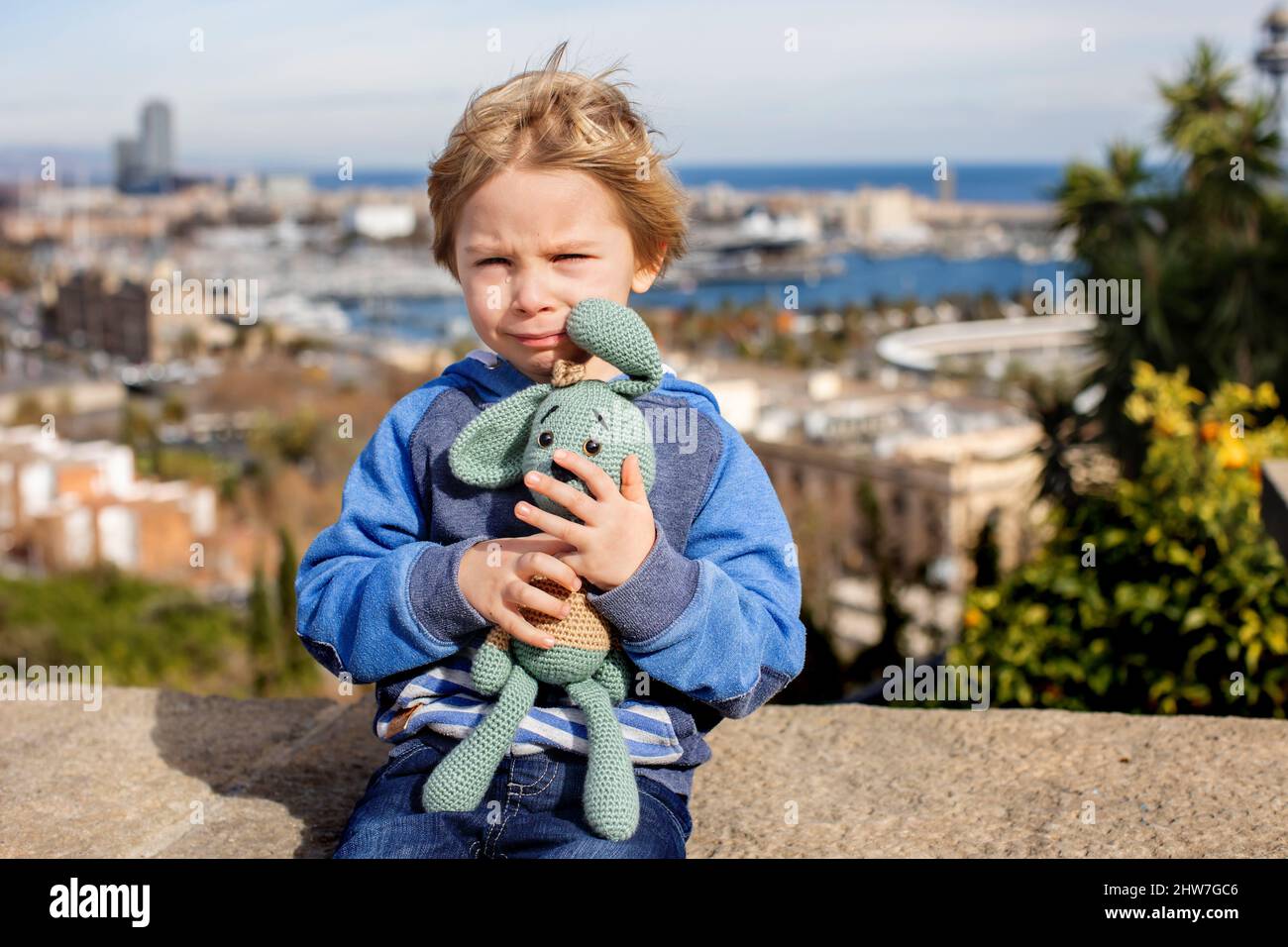 Cute little child tourist, holding knitted toy, crying, sitting on a ...