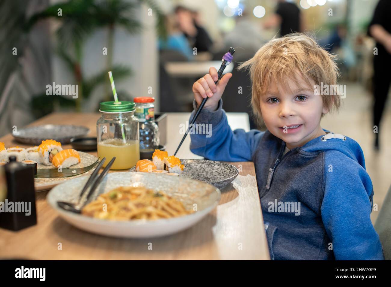 Child, eating japanese sushi and noodles with chopsticks in a ...